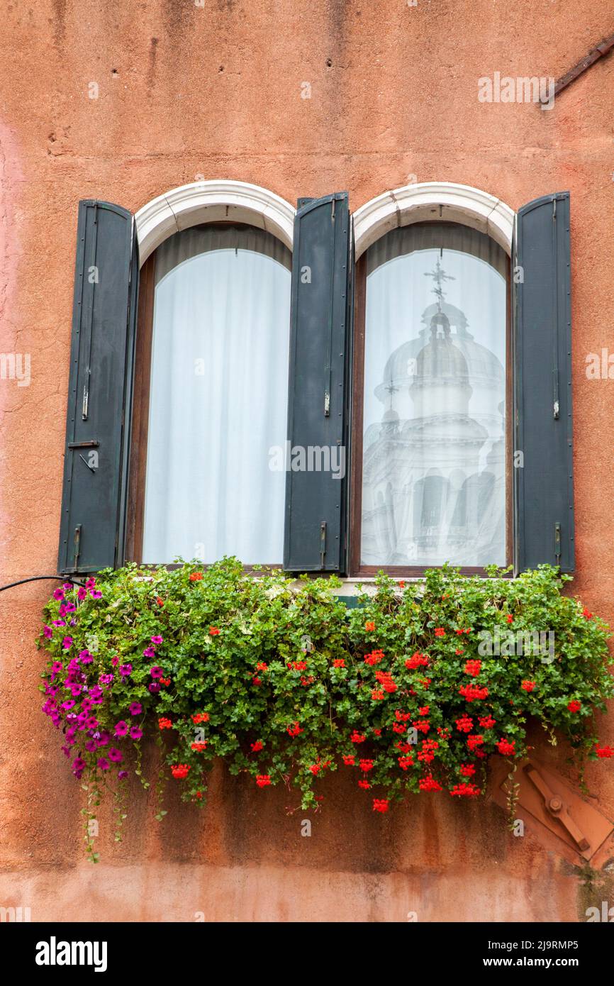 Italy, Venice. Window with shutters and flower boxes and reflection of ...