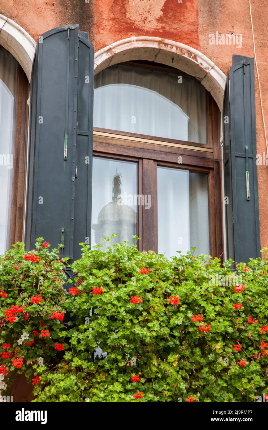 Italy, Venice. Window with shutters and flower boxes and reflection of ...