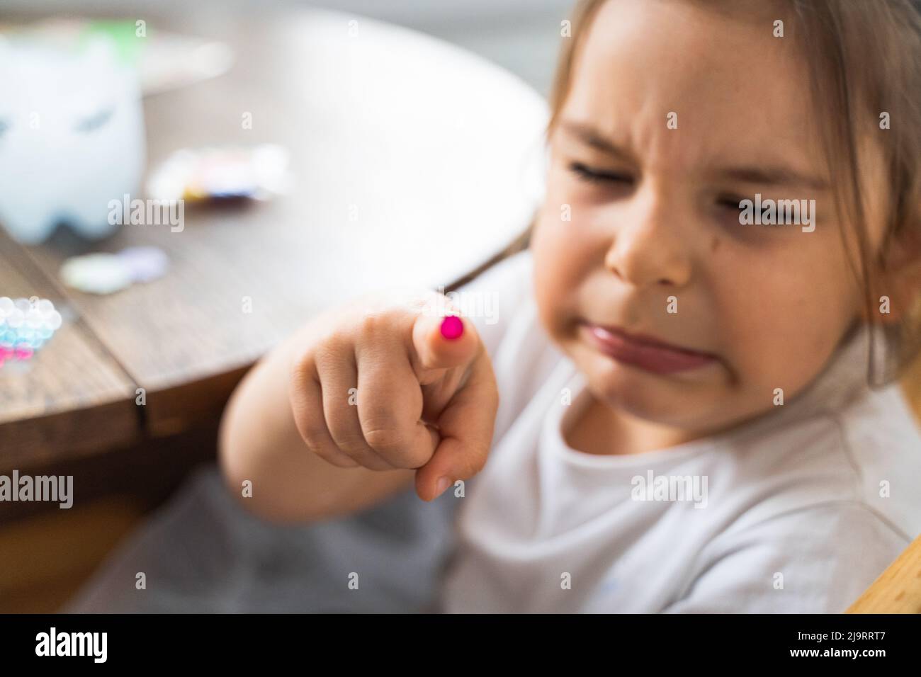 Unhappy child girl at preschool has problem with hand made crafts Stock ...