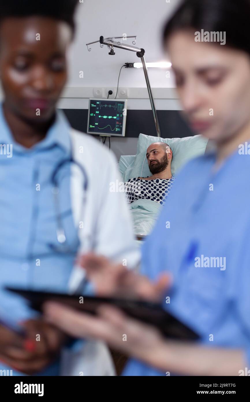Doctor and nurse reading digital test results on tablet for man with ...