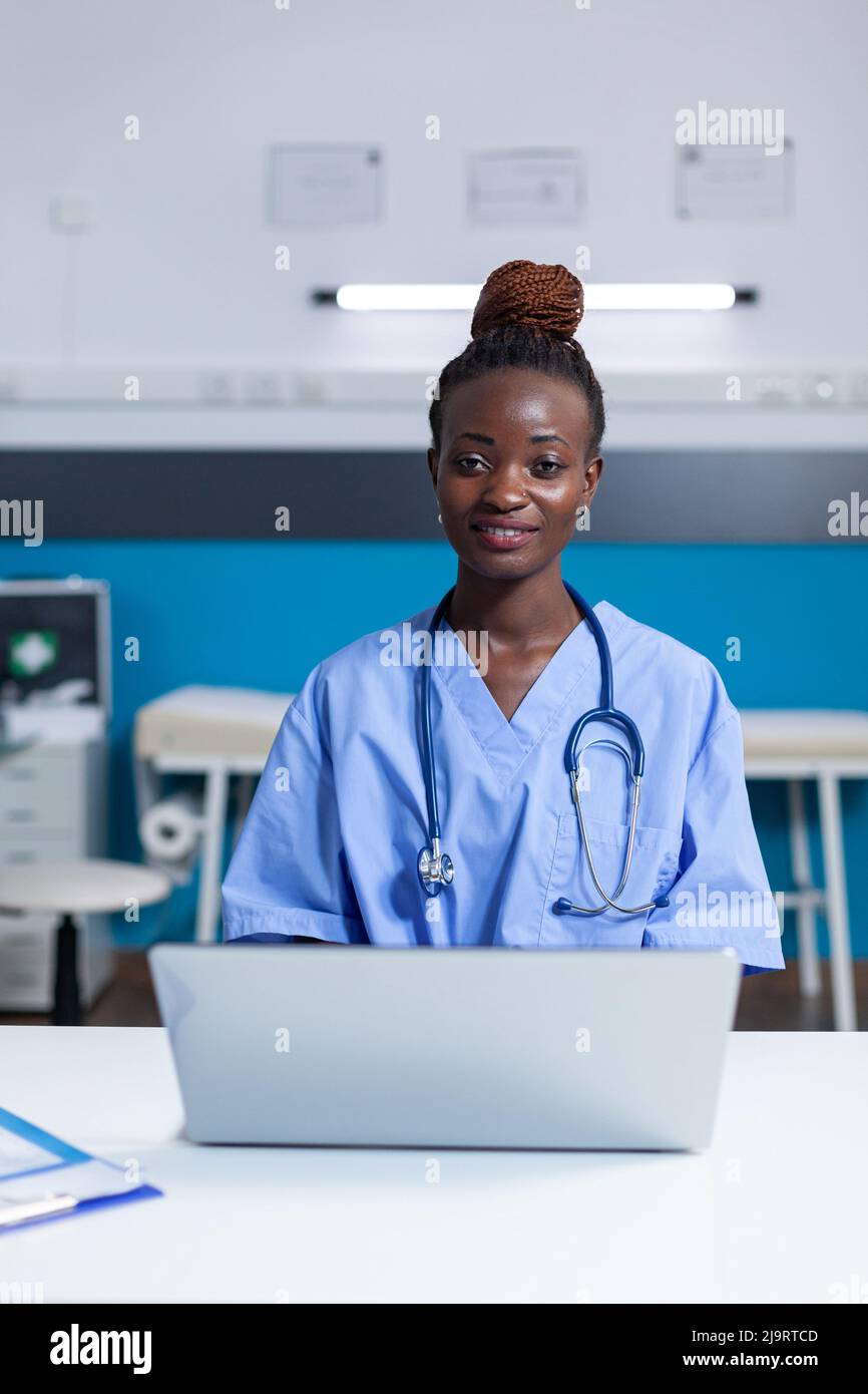 Healthcare clinic staff sitting at office desk in healthcare facility cabinet while using laptop ...