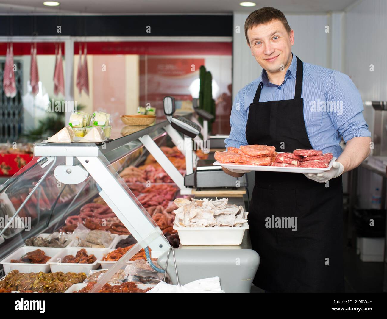 Butcher working behind counter Stock Photo - Alamy