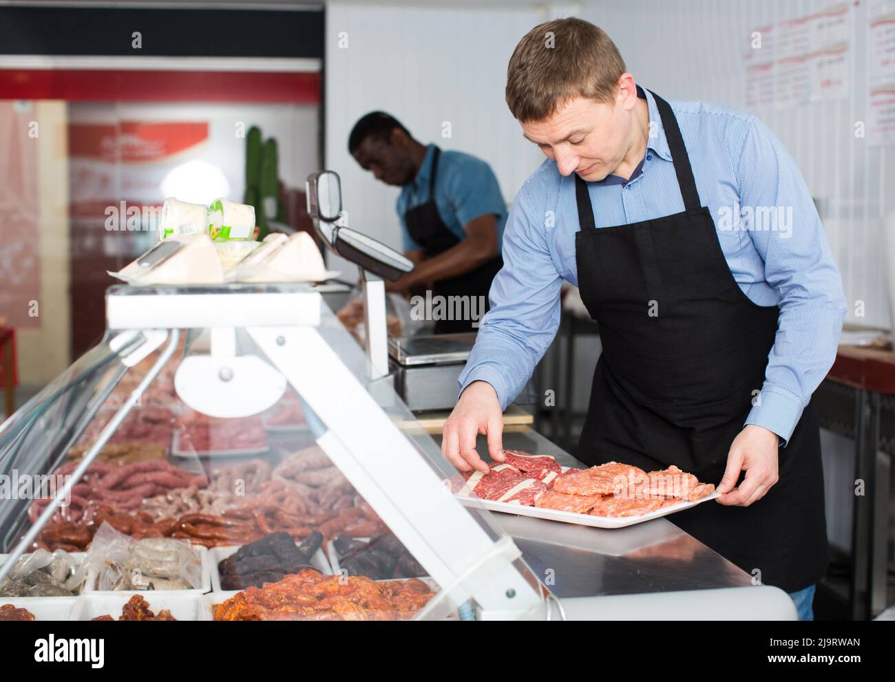 Butchers working behind counter Stock Photo - Alamy