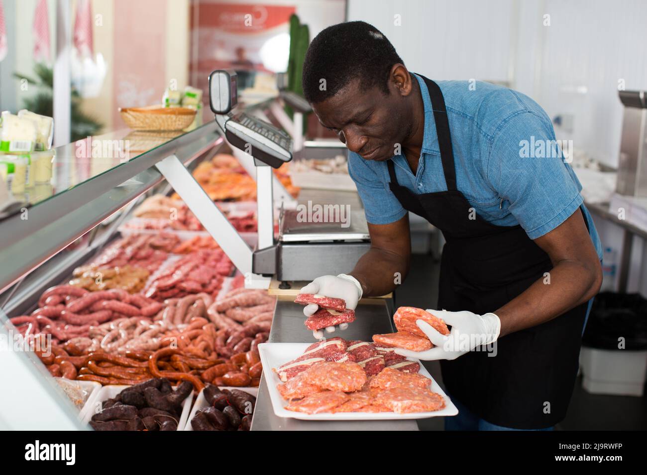 Butcher working behind counter Stock Photo - Alamy