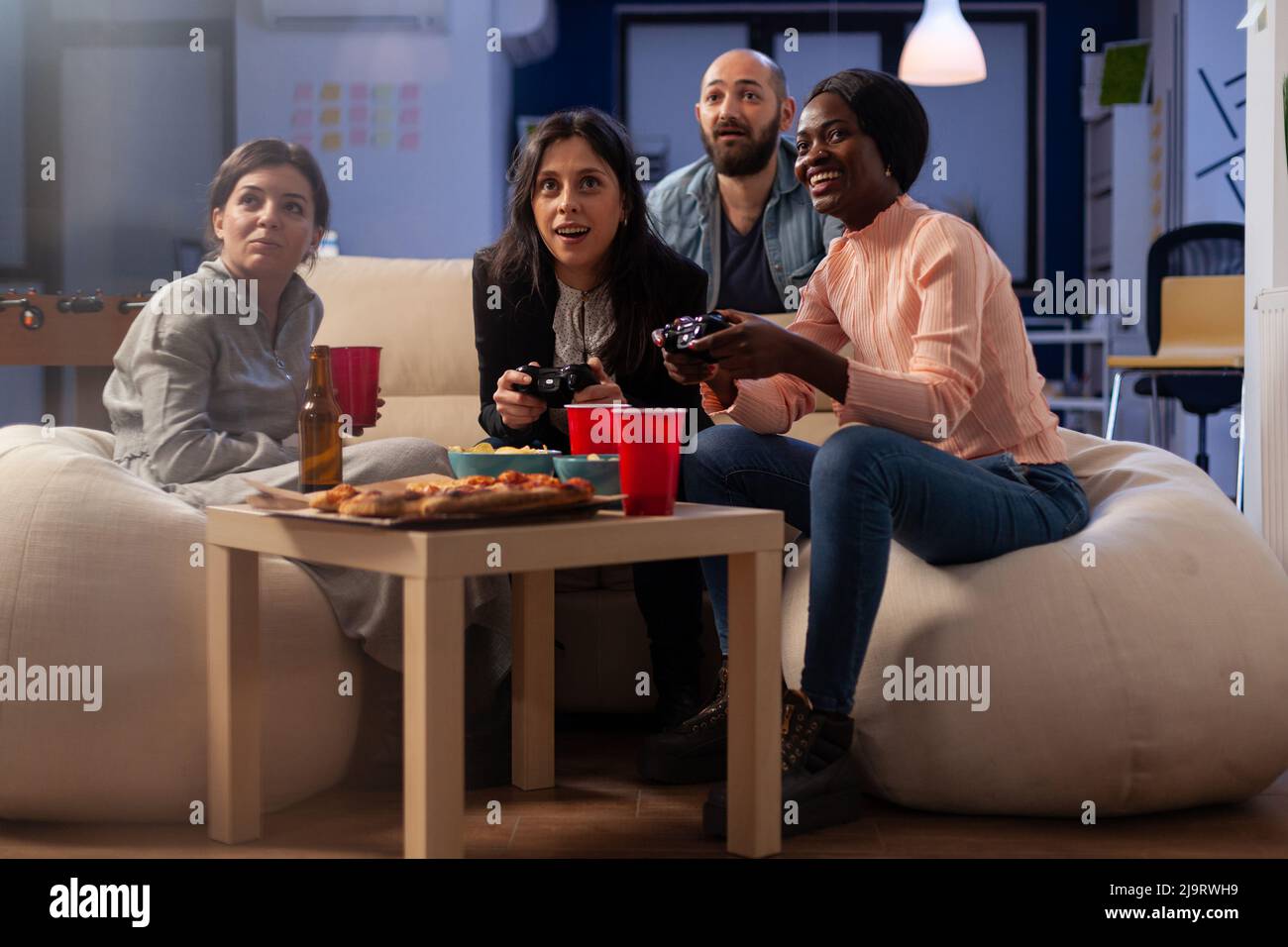 Cheerful workmates using joystick to play online videogames, enjoying ...