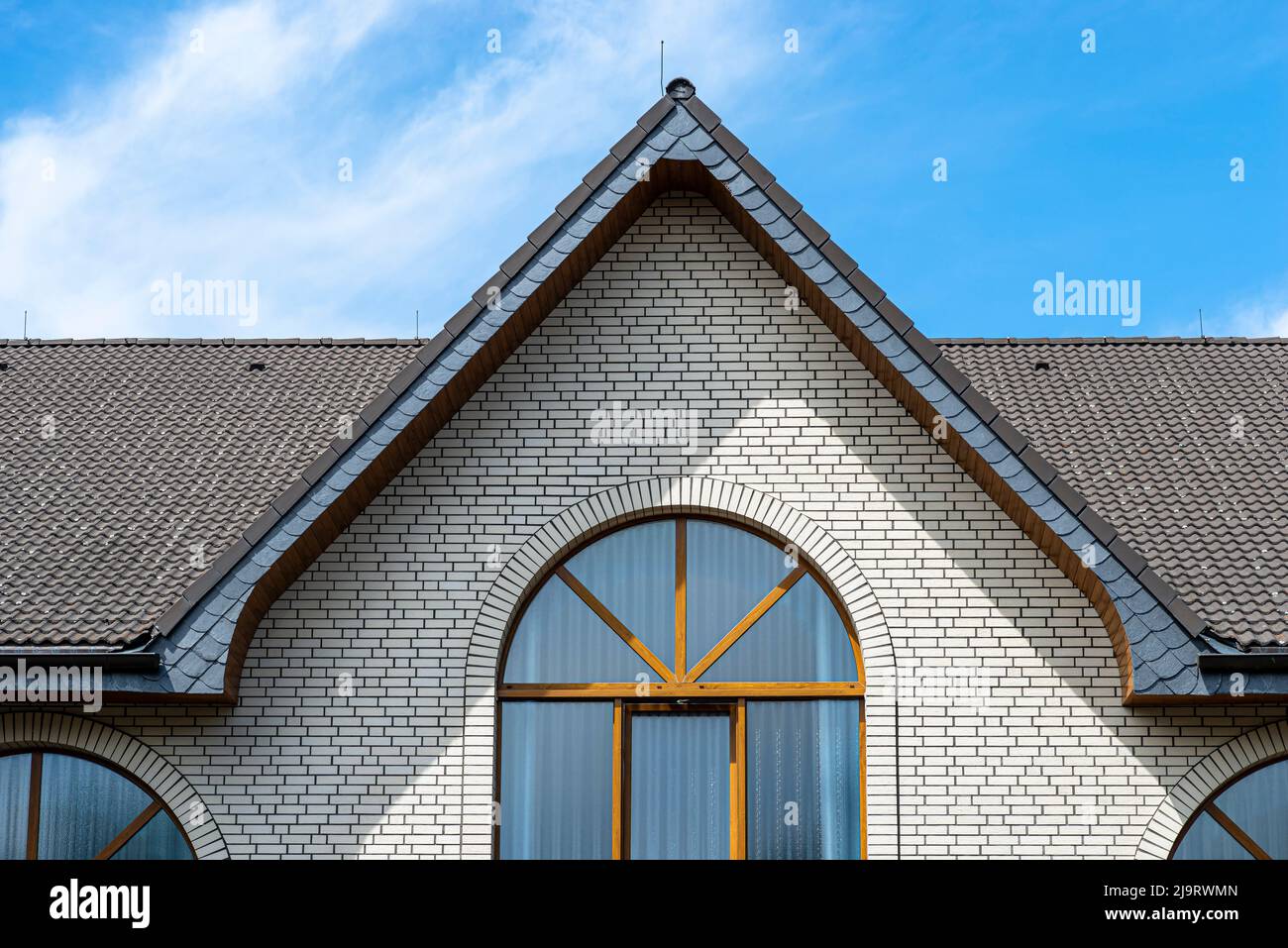The church has a classic facade of white brick and a conical roof ...