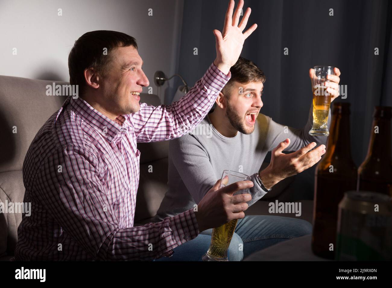 Two happy men emotionally watching tv at home Stock Photo - Alamy