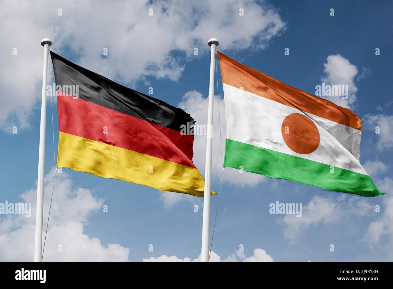 Germany and Niger two flags on flagpoles and blue cloudy sky background ...