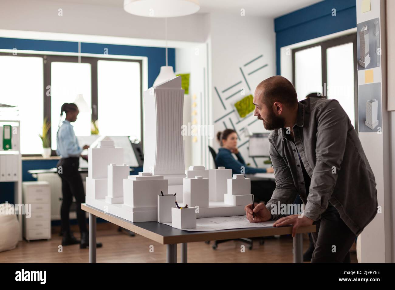 Man working on architectural design at office while looking at laptop ...