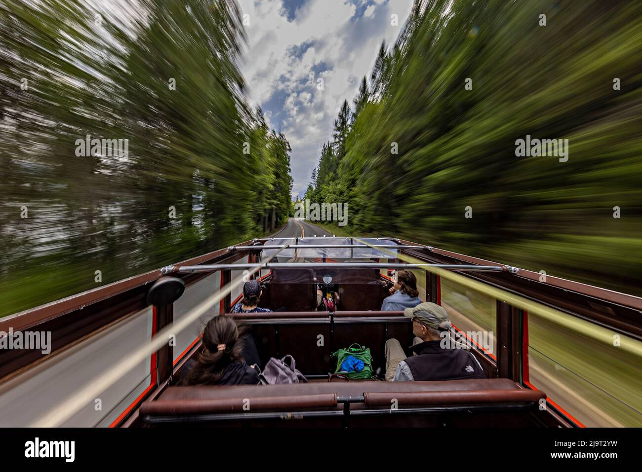 Iconic Red Jammer bus in motion in Glacier National Park, Montana, USA ...