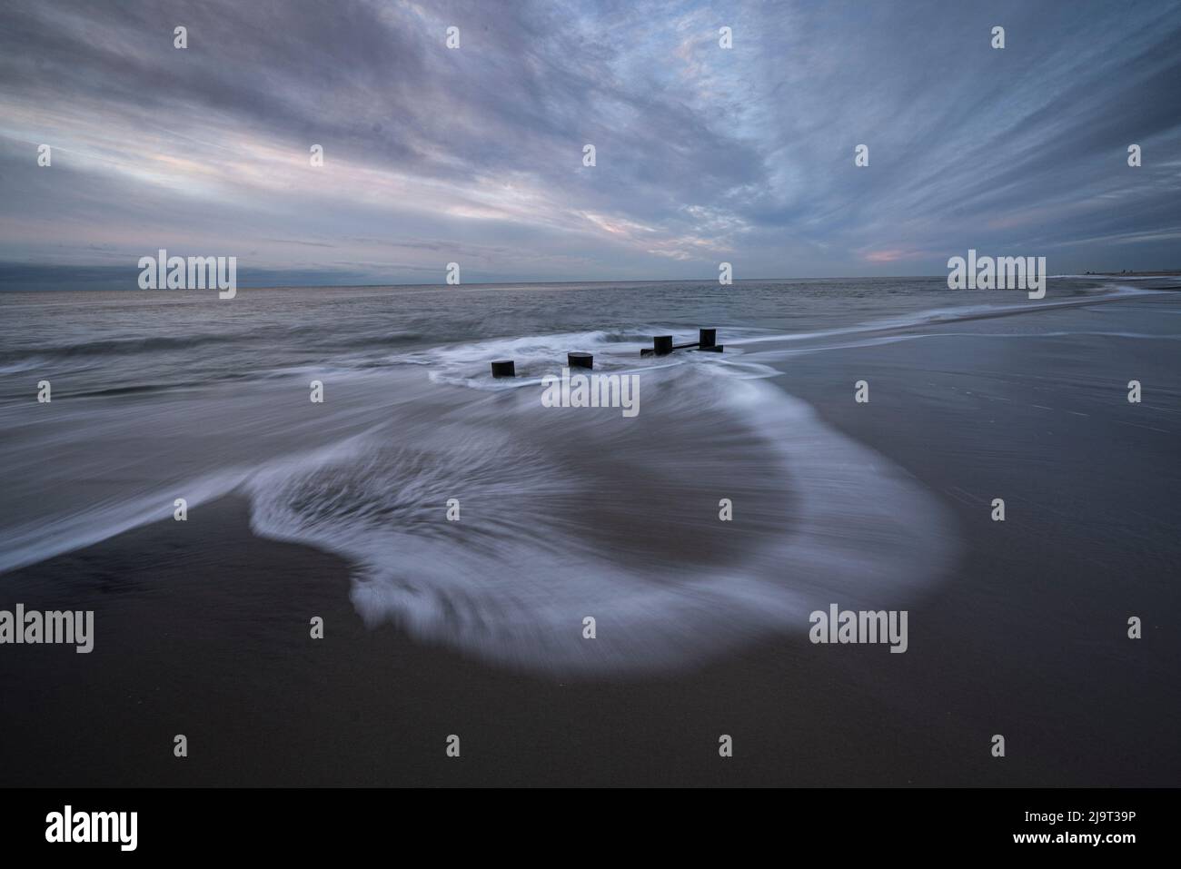 USA, New Jersey, Cape May National Seashore. Pier stumps on cloudy ...