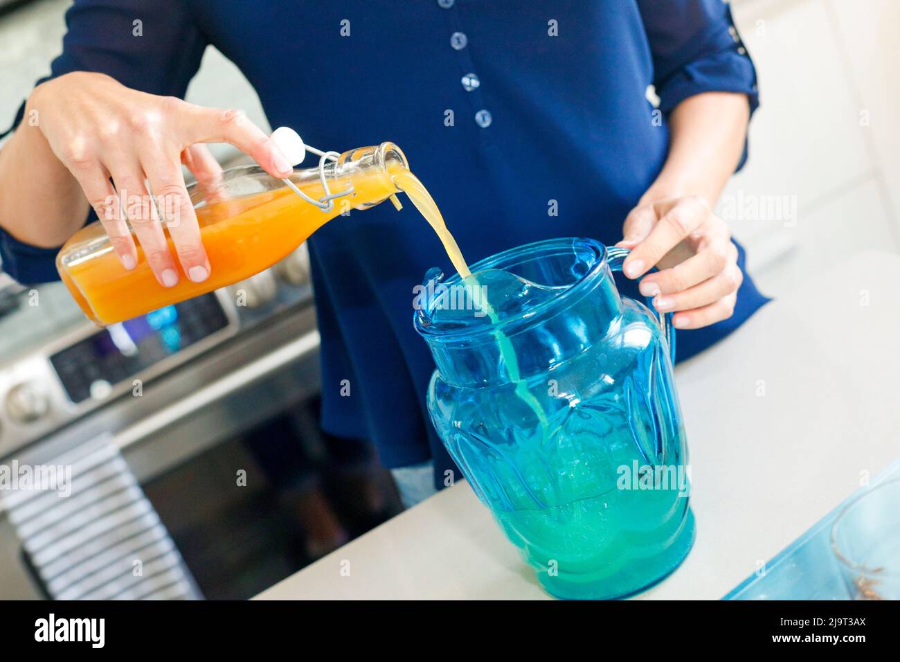 Person pouring orange juice into a pitcher. (MR Stock Photo - Alamy