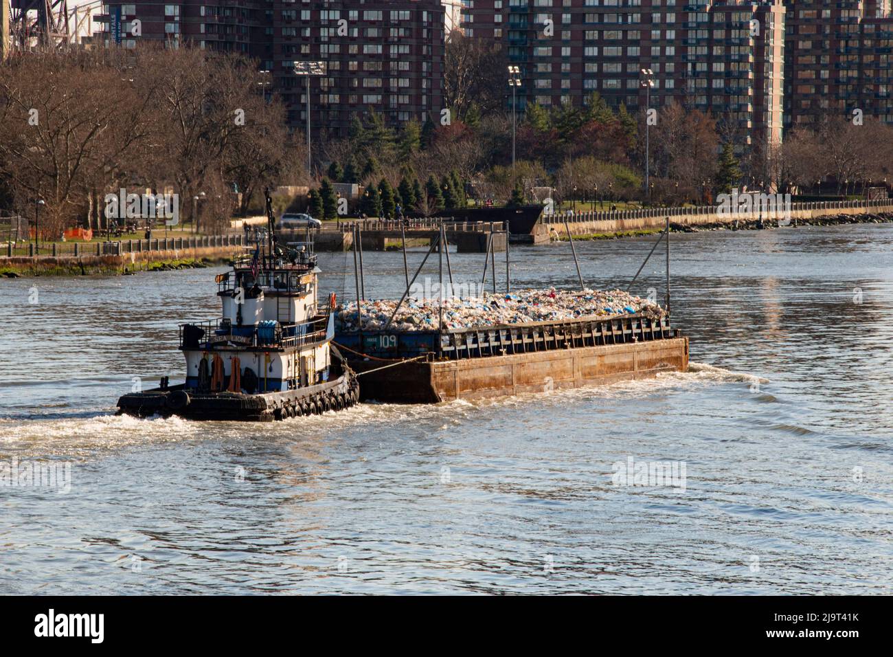 USA, New York City, Manhattan, Upper East Side. barge hauling trash ...