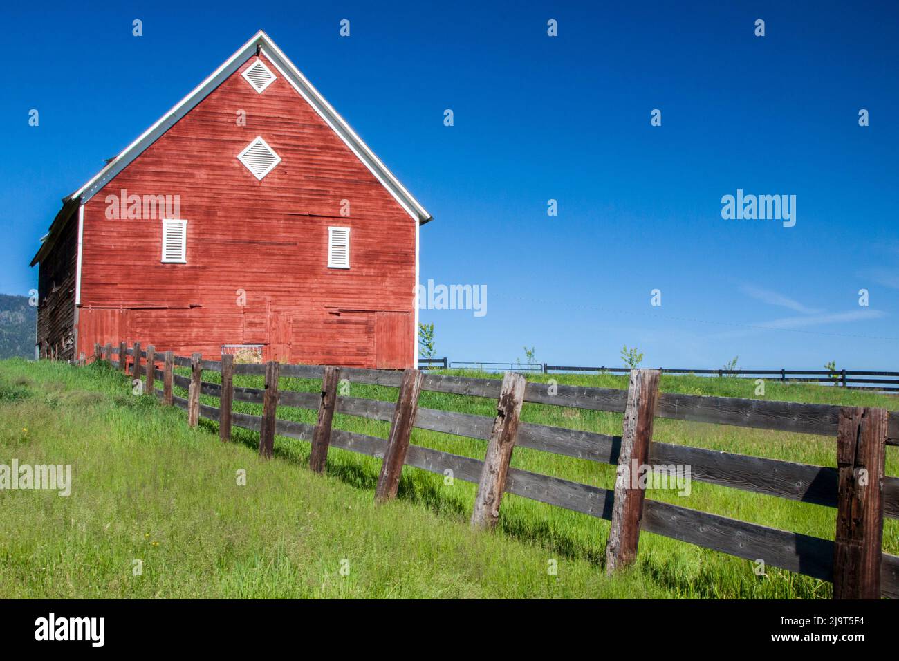USA, Oregon, Joseph. Red barn and fence near the Wallowa Mountains in ...