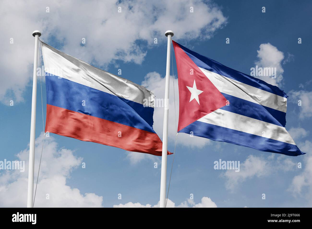 Russia and Cuba two flags on flagpoles and blue cloudy sky background ...