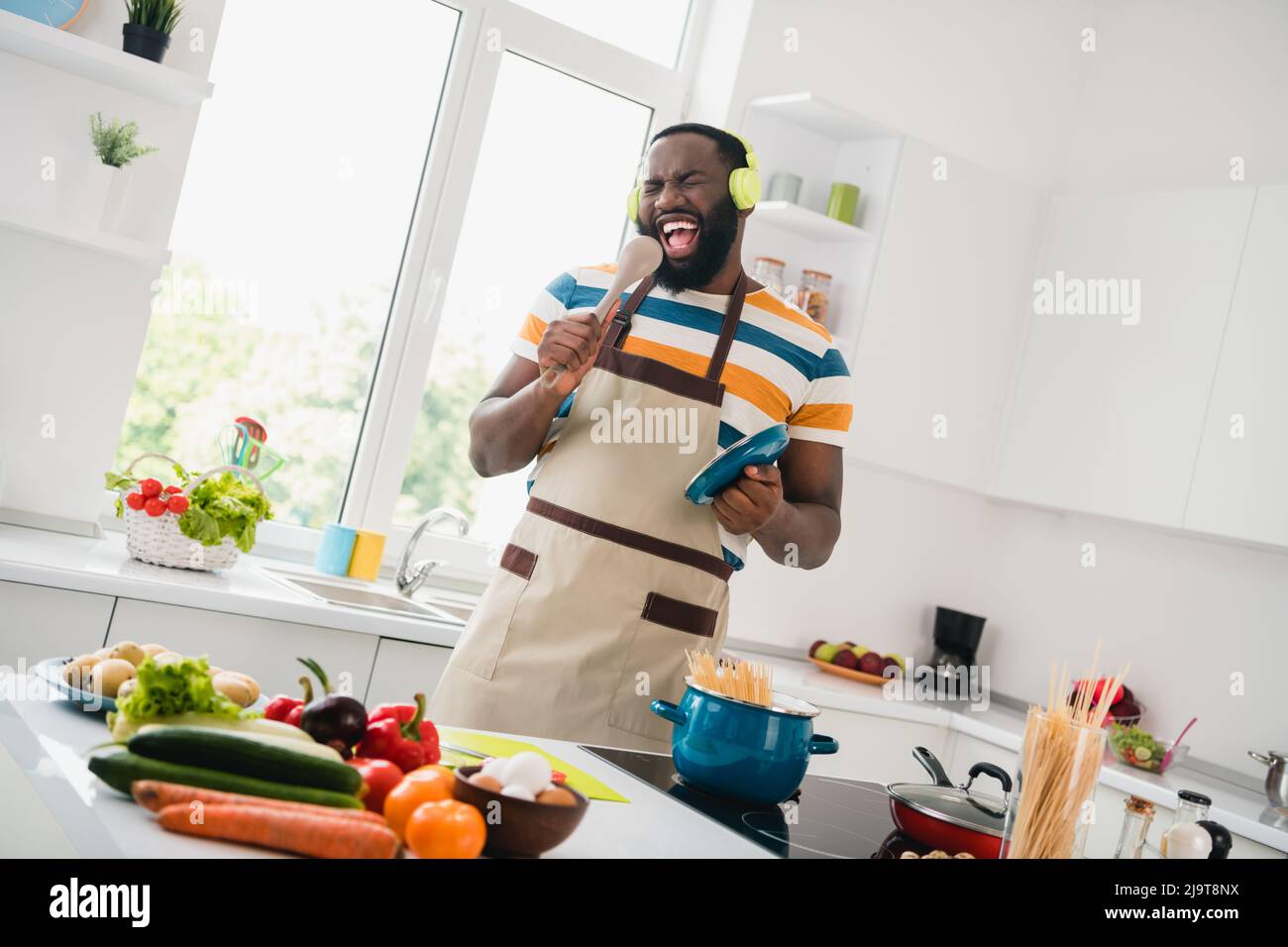 Photo of young excited guy have fun enjoy cooking listen radio ...