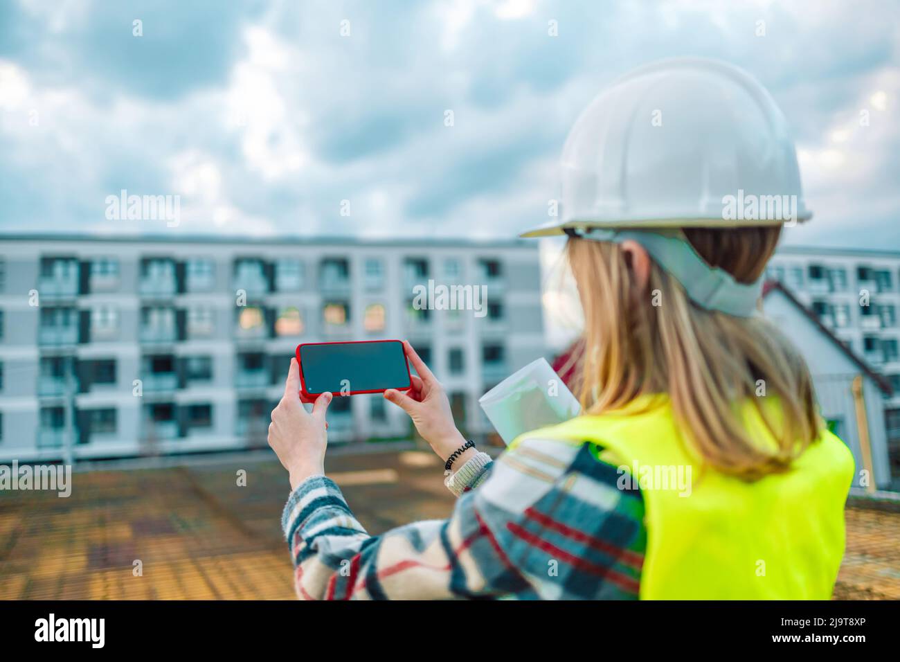 Female architect taking a photo at the construction site checking the ...