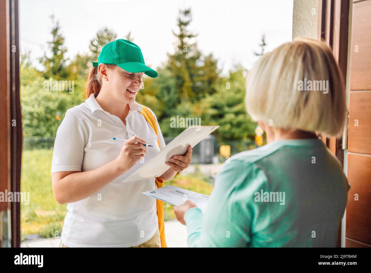 Woman courier making a delivery to a customer at their home. r ...
