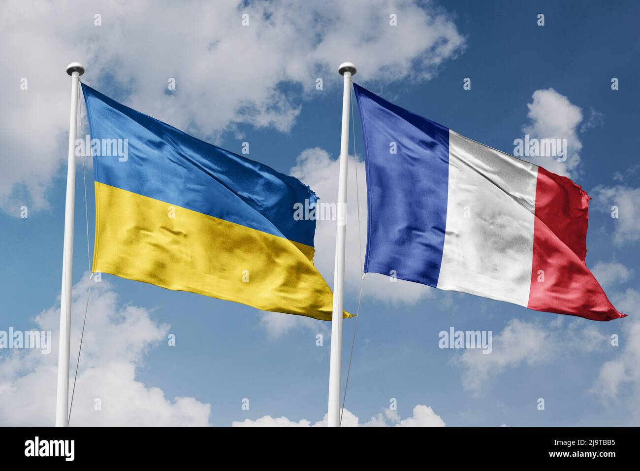 Ukraine and France two flags on flagpoles and blue cloudy sky ...
