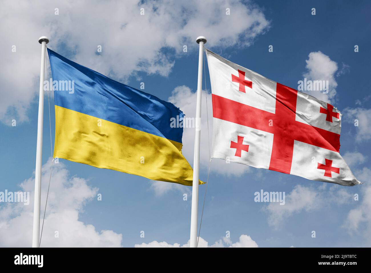 Ukraine and Georgia two flags on flagpoles and blue cloudy sky ...
