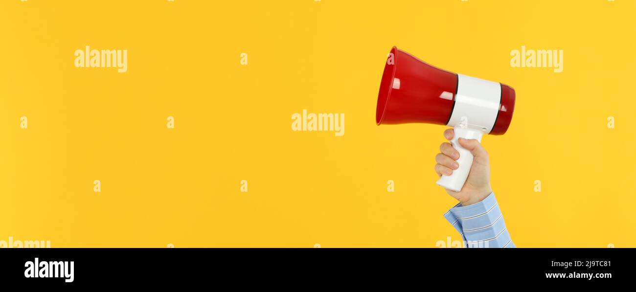 Female hand with megaphone on yellow background Stock Photo - Alamy