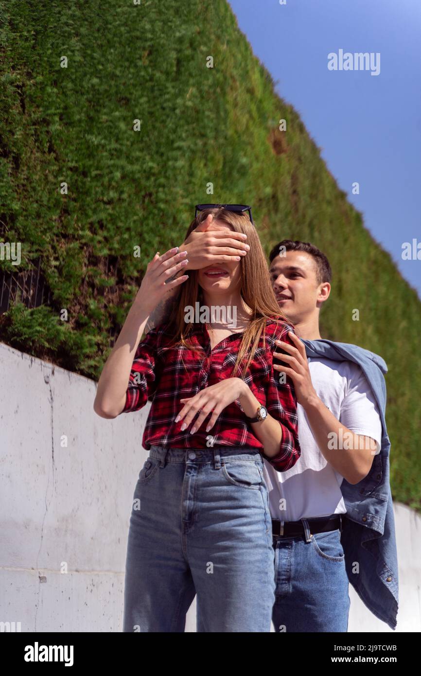 Cute couple flirting with eachother while the boy is covering her eyes ...
