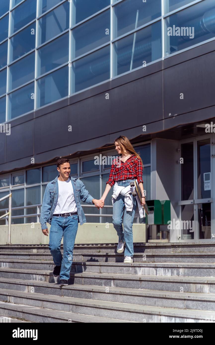 Cute couple walking on the stairs in front of the building while ...