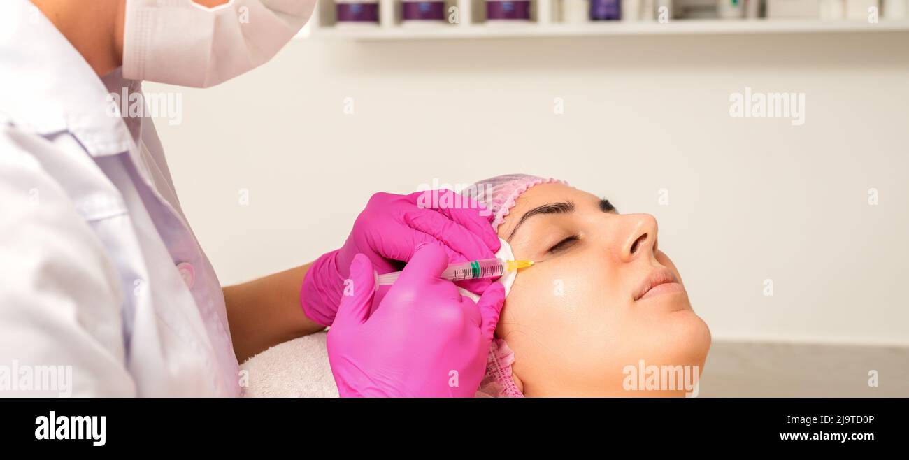 The young white woman is getting rejuvenating facial injections with ...