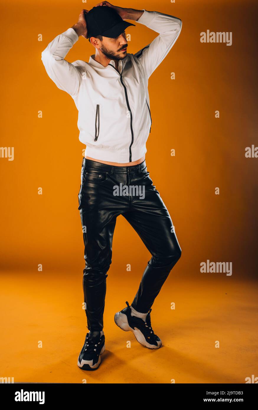 Cool young man dressed in white wind jacket, blacked pants and sneakers ...