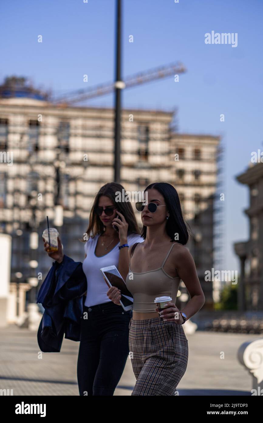 Young and beautiful assistent is talking on the phone while walking ...