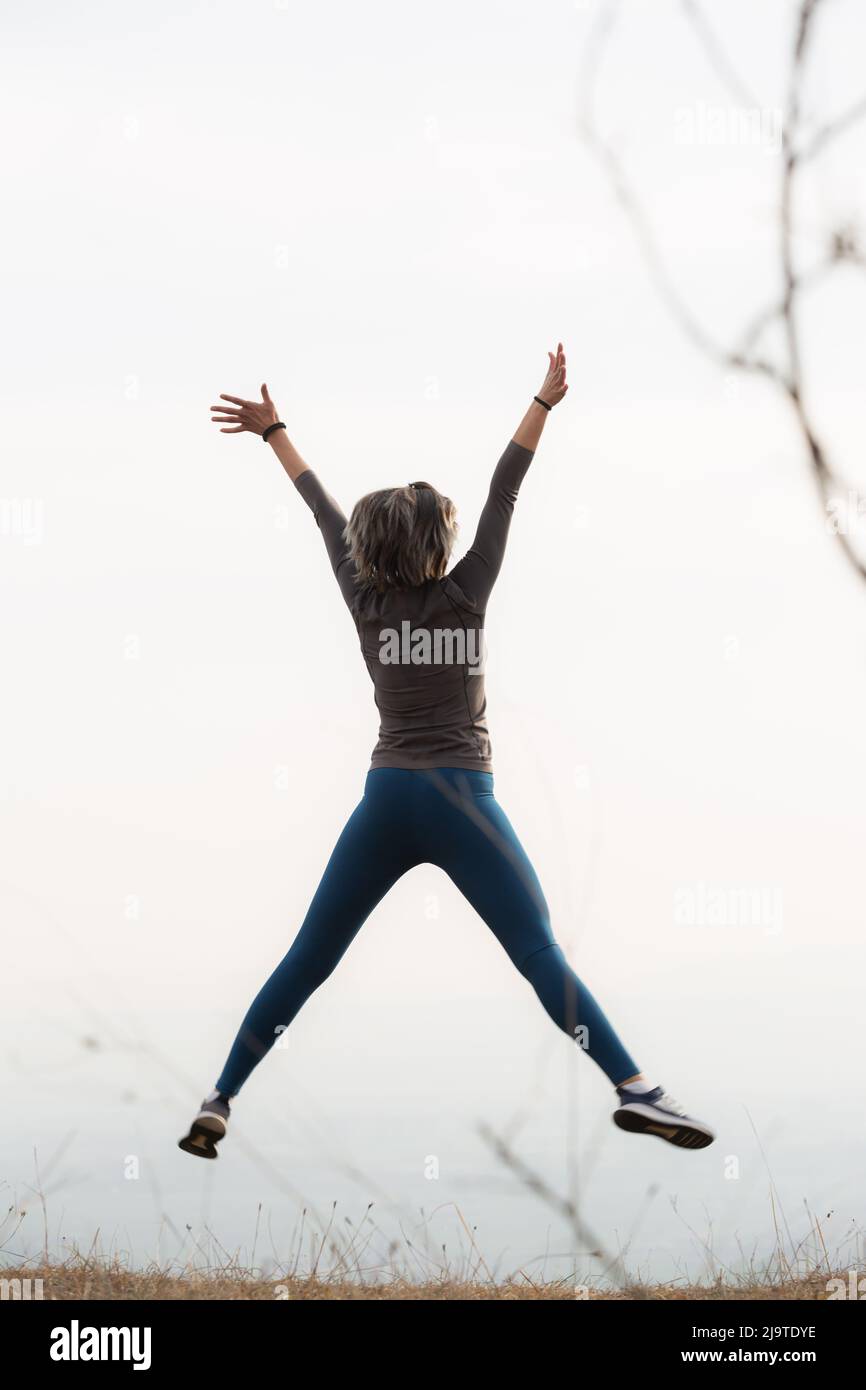 Amazing and active woman is jumping while being happy Stock Photo - Alamy