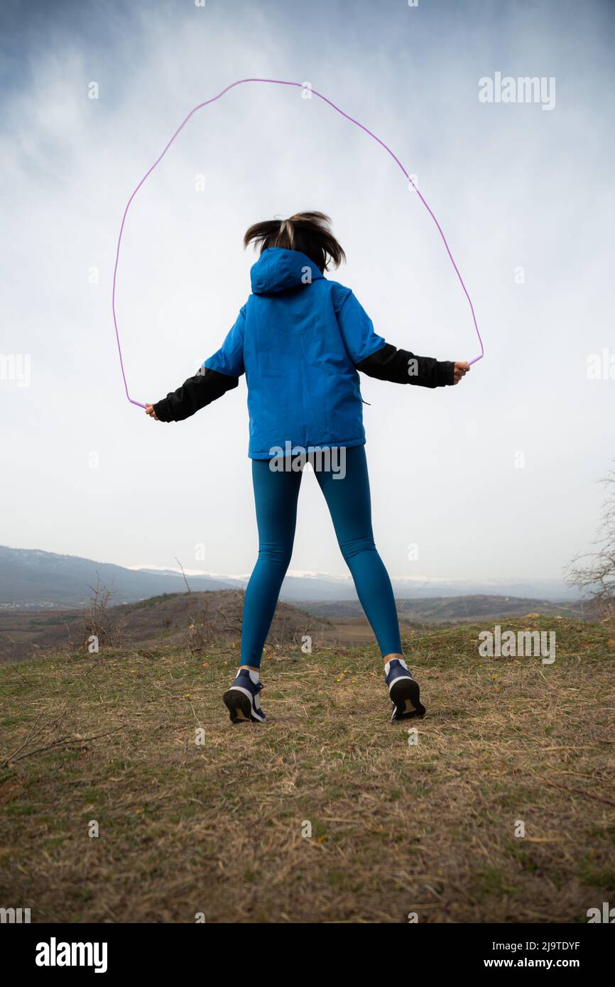 Amazing and active woman is doing a jumping rope exercise in the forest ...