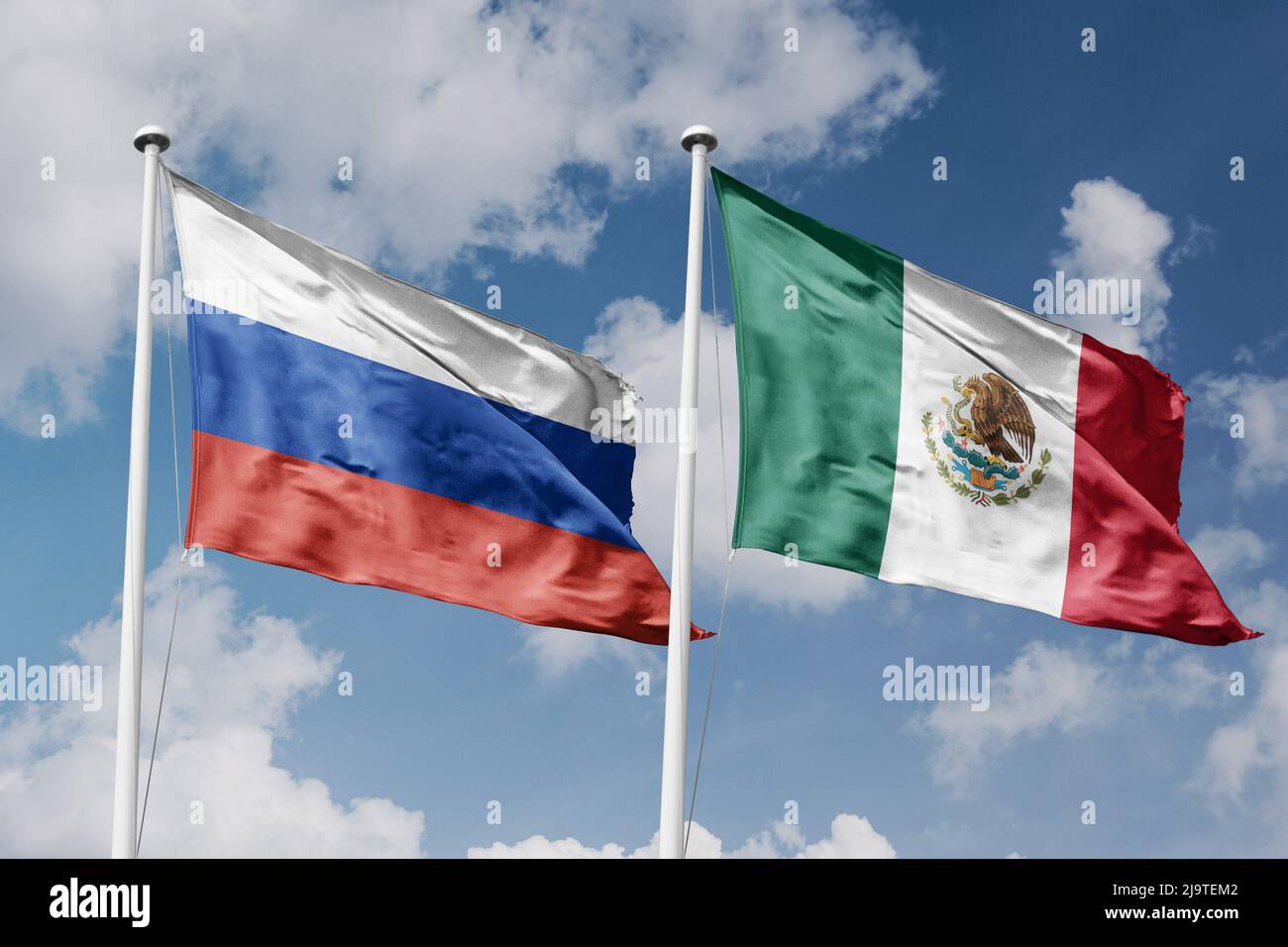 Russia and Mexico two flags on flagpoles and blue cloudy sky background ...