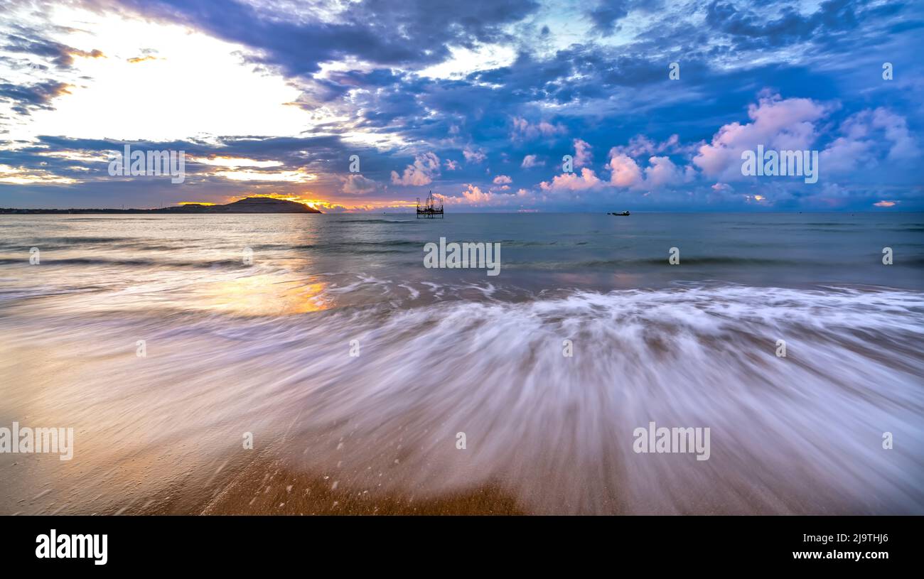 Beautiful sunrise on the beach waves lapping at the shore of the soft ...
