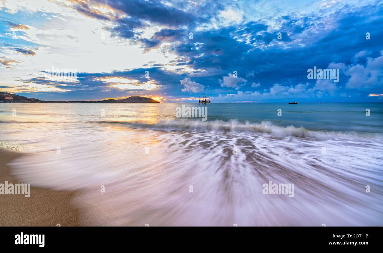 Beautiful sunrise on the beach waves lapping at the shore of the soft ...