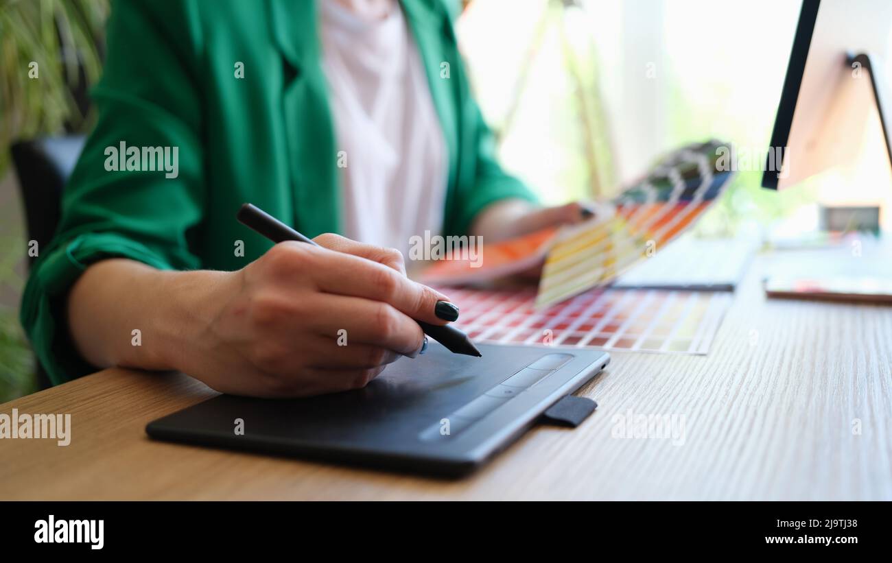 Designer draws sketches on graphics tablet and holds color palette ...