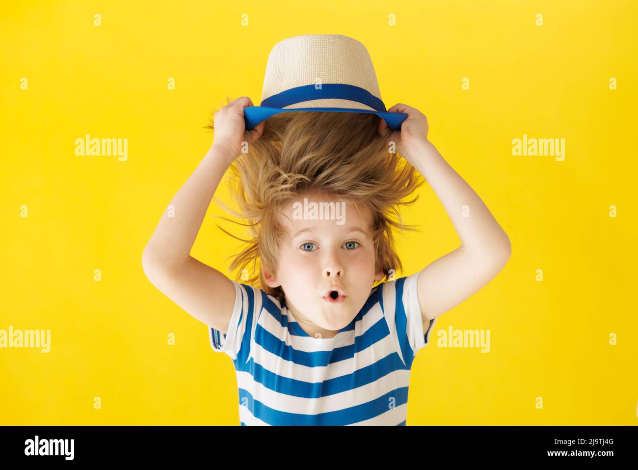 Surprised child holding face. Shocked kid against yellow background ...