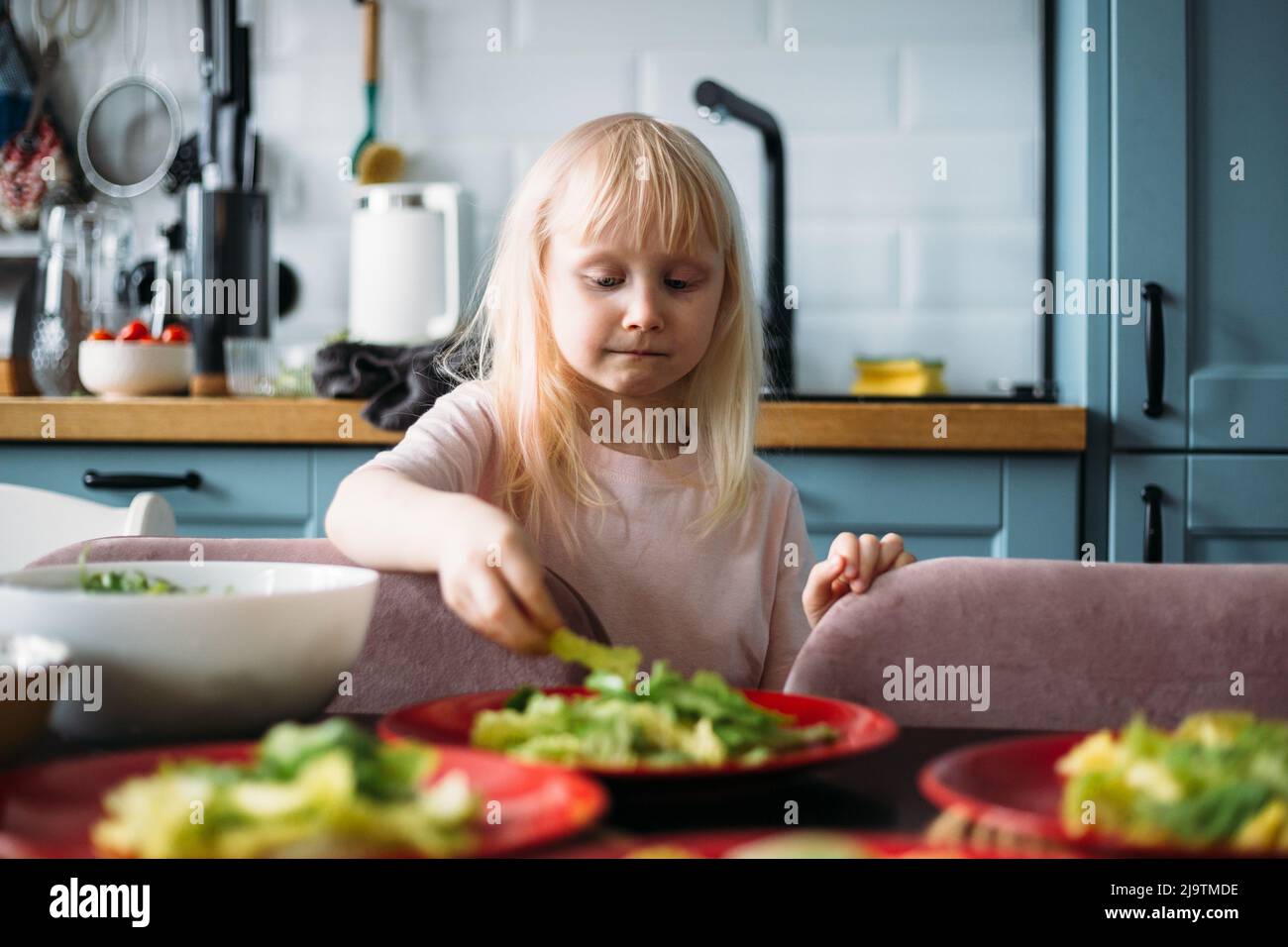 Little blonde girl is helping to prepare dinner in the kitchen Stock ...
