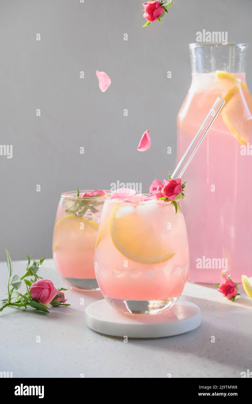 Freshness lemonade with rose gin, lemon and roses with sunny shadow on ...