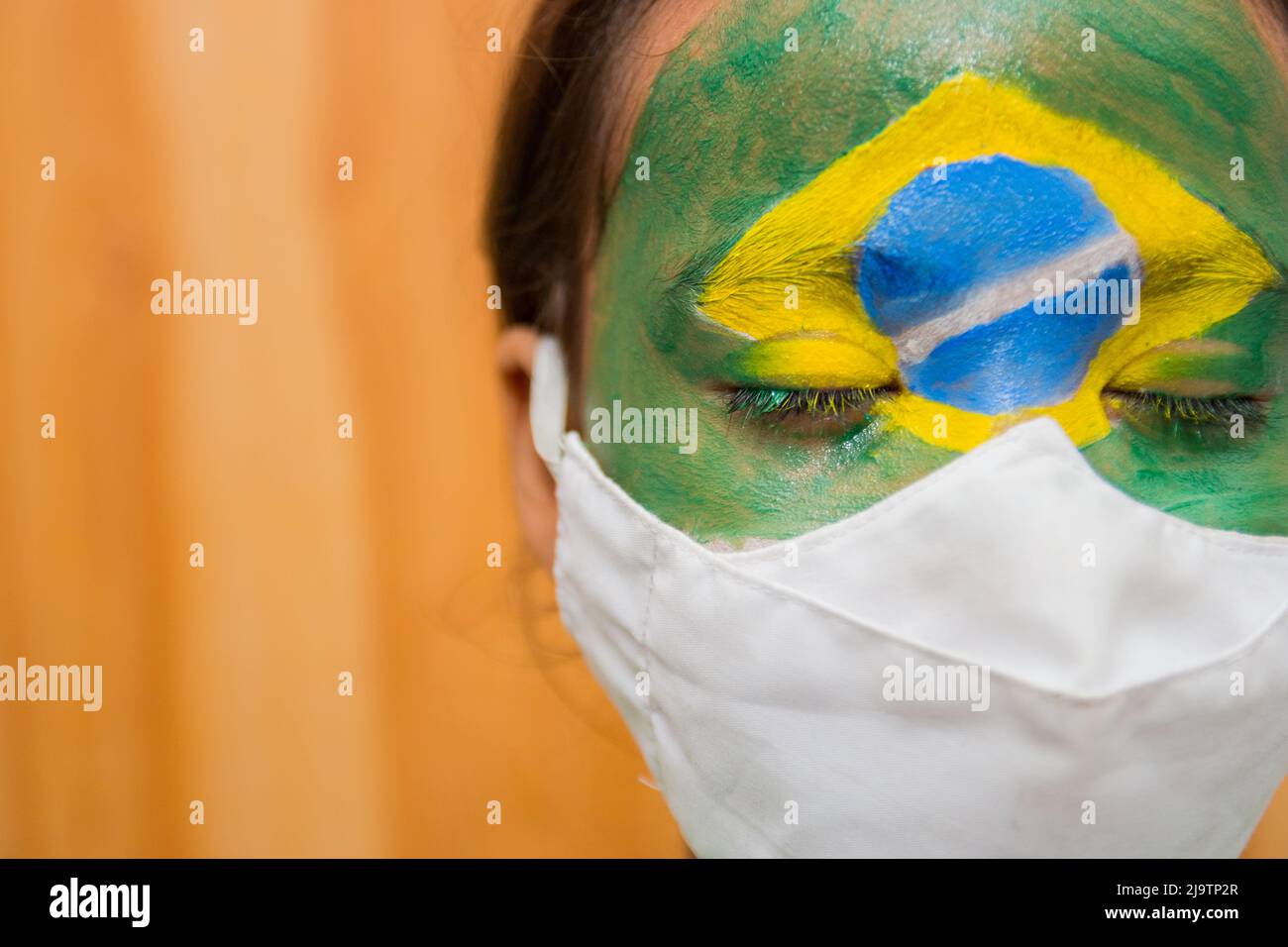 child with a mask with his face painted with the flag of Brazil Stock ...
