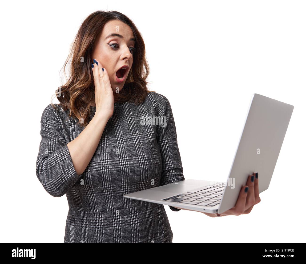Young businesswoman holding her laptop with an expression of shock ...