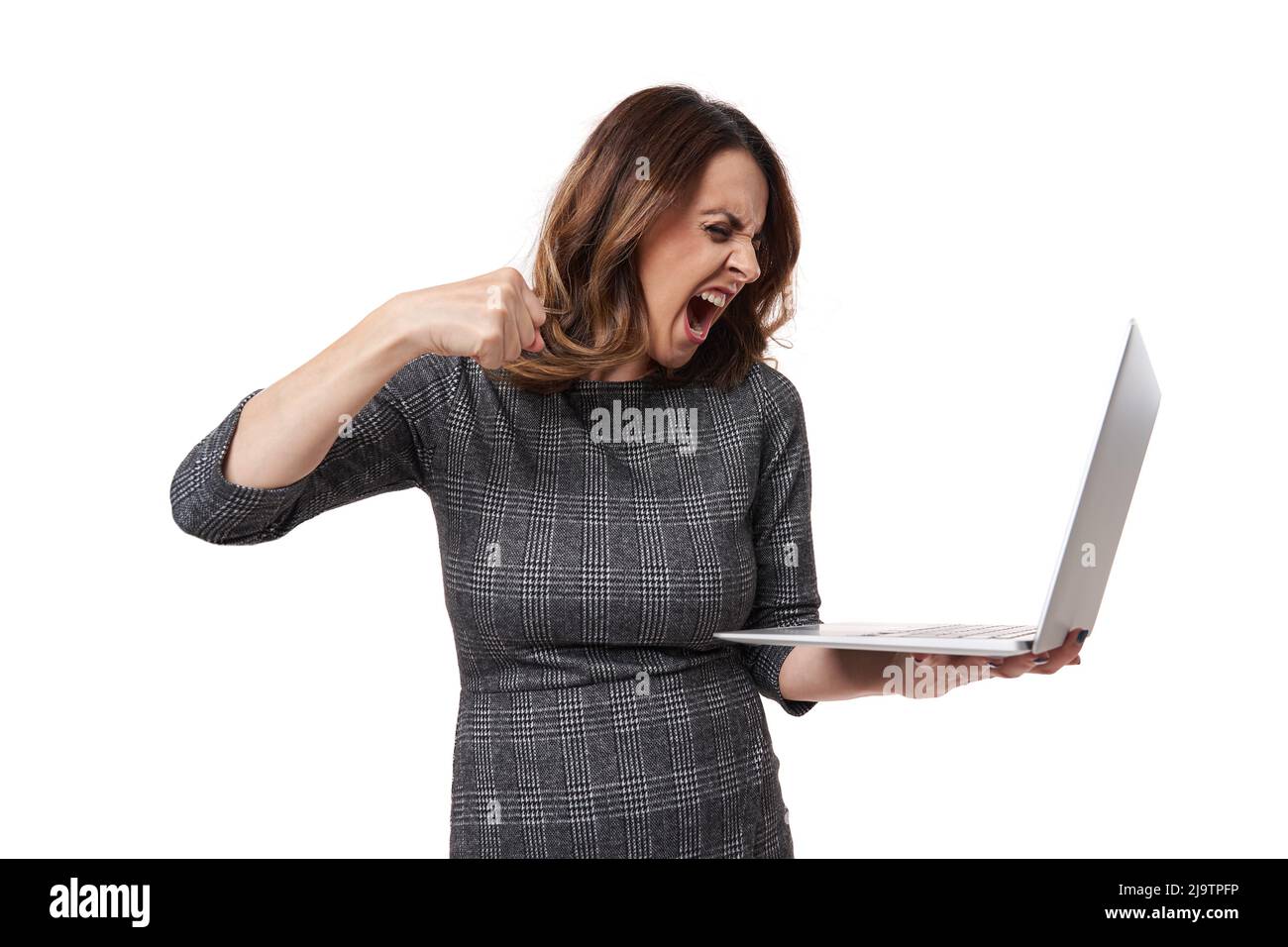 Extremely frustrated and angry young businesswoman, holding her laptop ...
