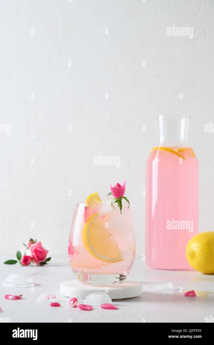 Pink alcoholic rose beverage or lemonade, cocktail with rose flowers on ...