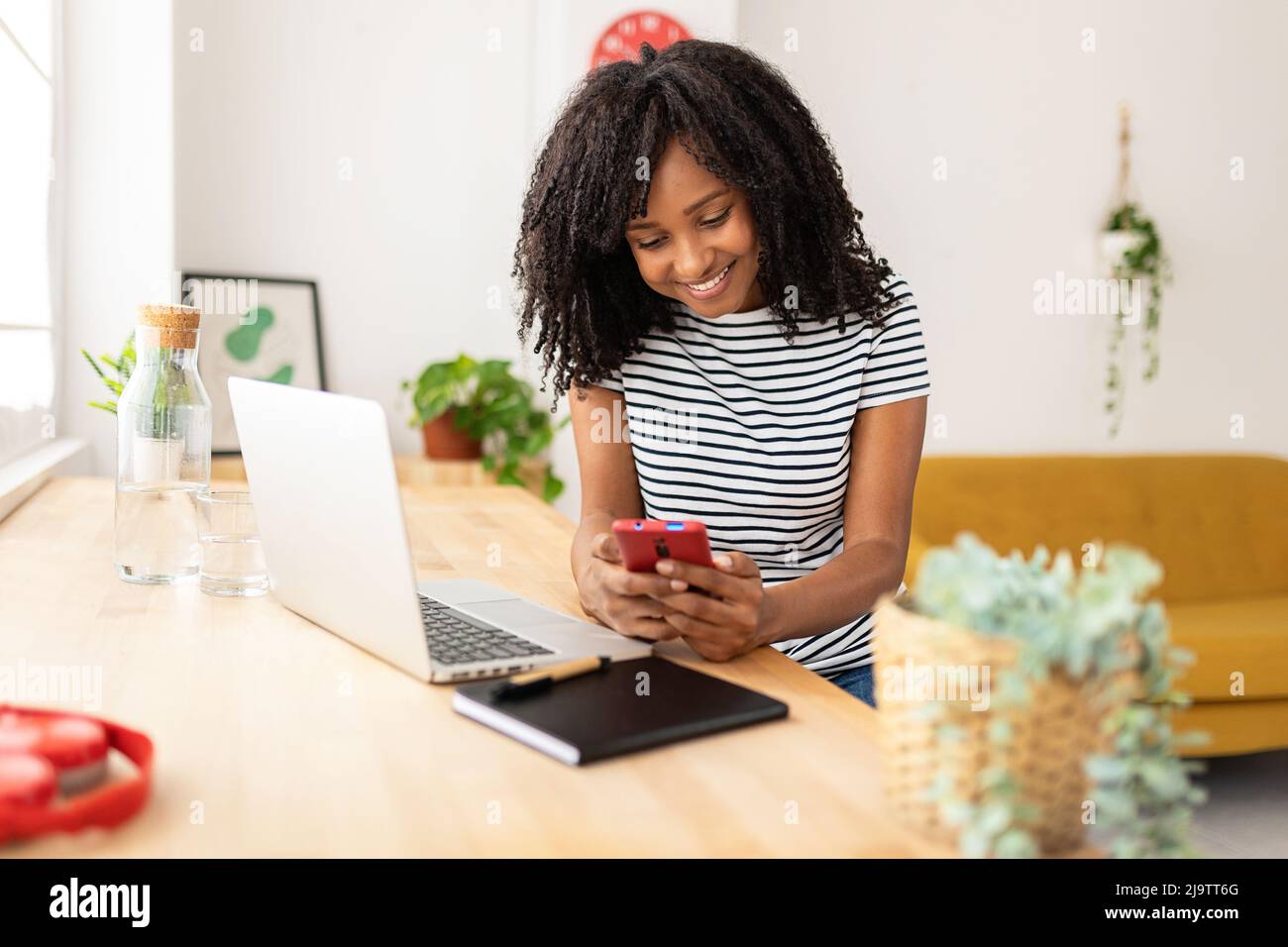 Young hispanic american woman using mobile phone while working on ...