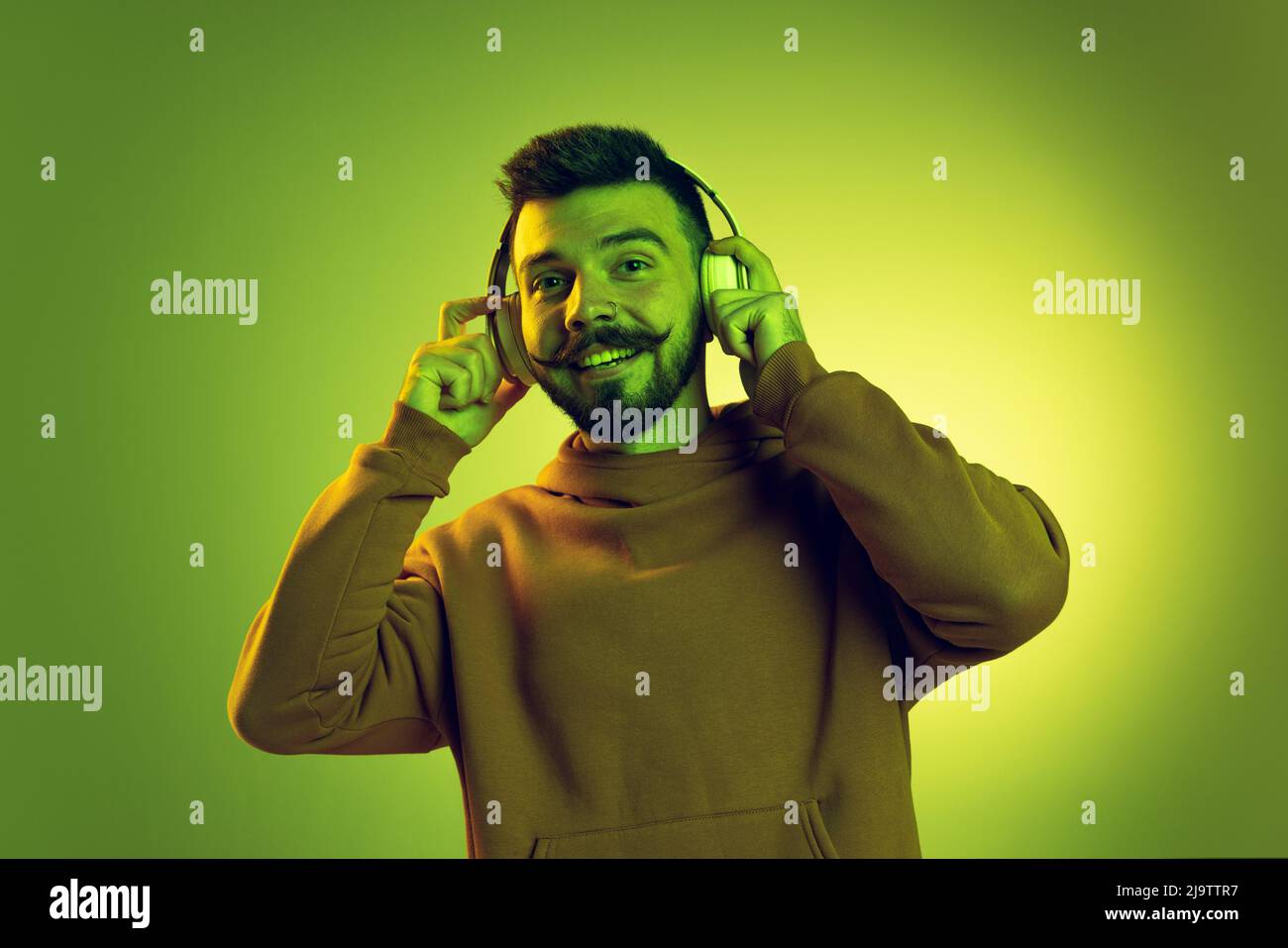 Portrait of young man with stylish moustache listening to music in ...