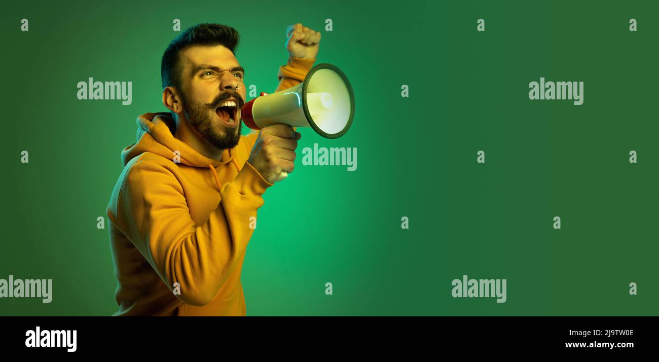 Portrait of young man in casual cloth shouting in megaphone isolated ...