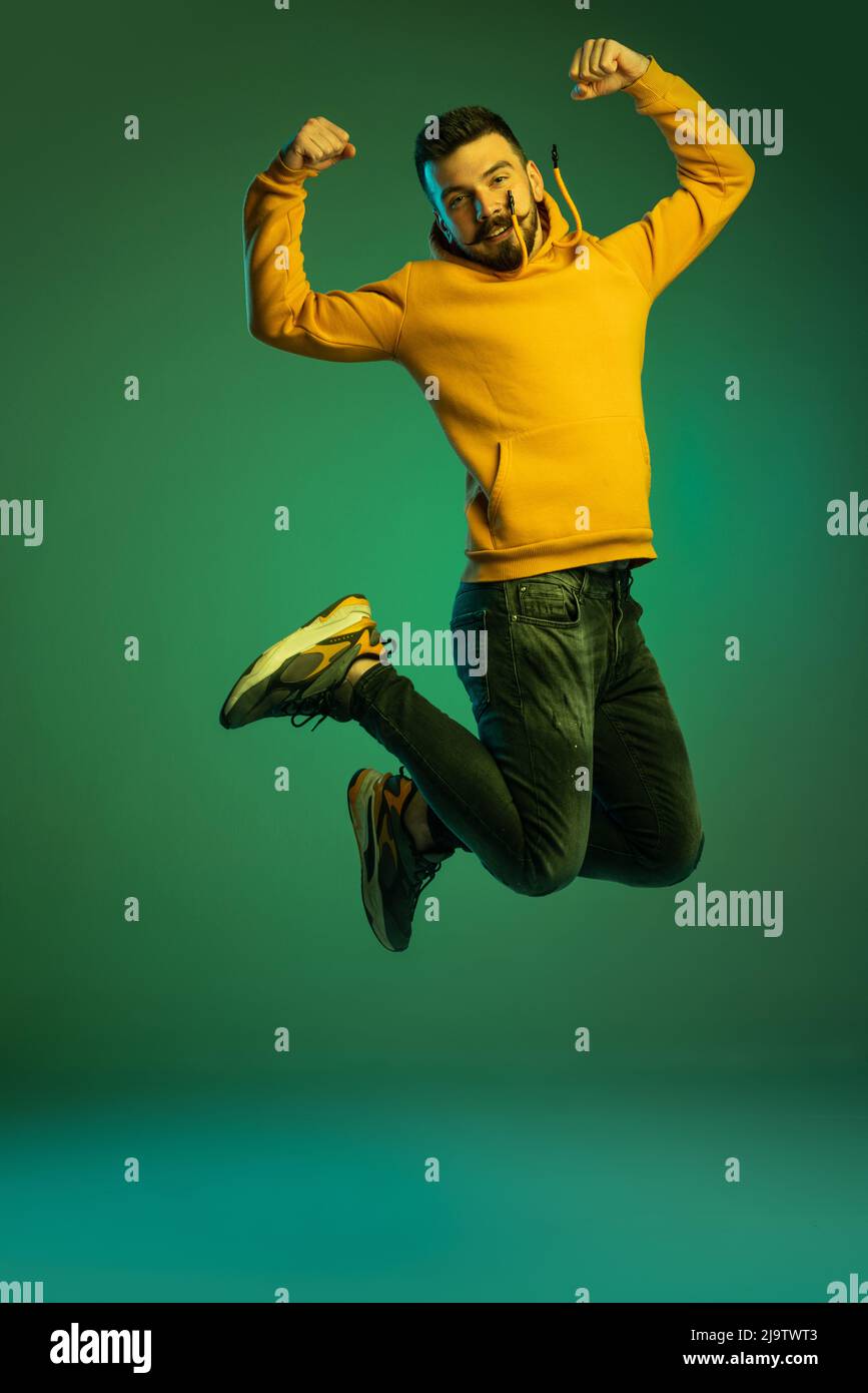 Full-length portrait of young man in casual cloth jumping, posing ...