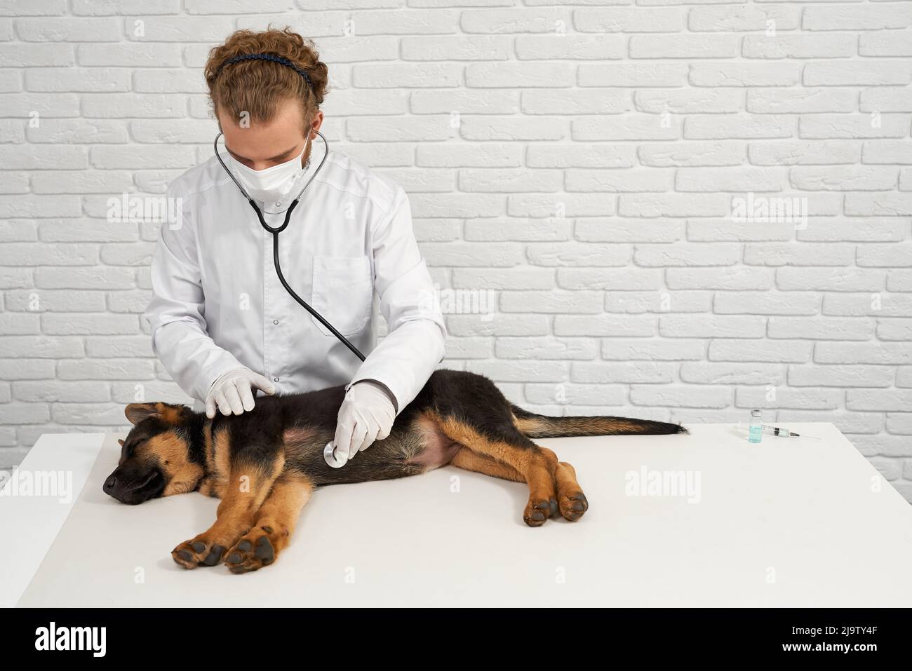 Front view of medical worker in coat and gloves using stethoscope for ...