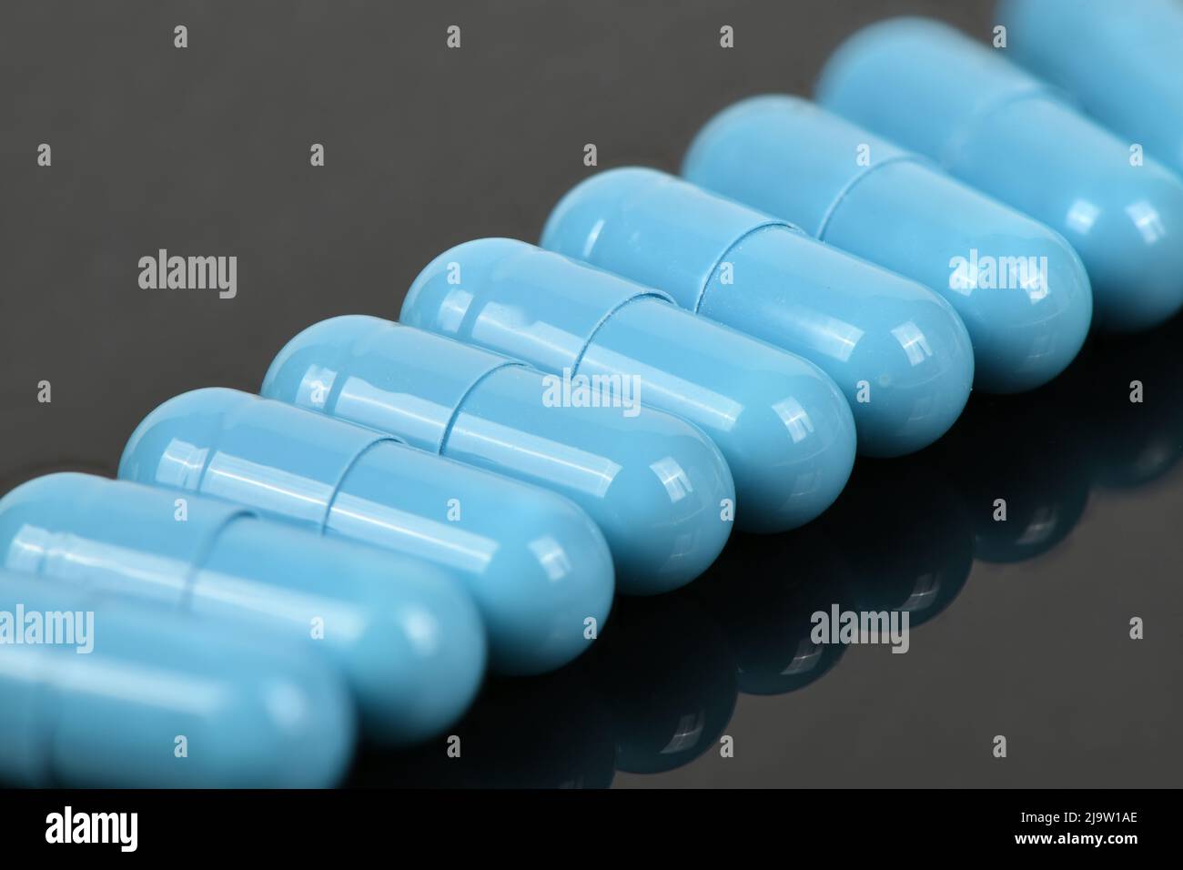 Blue medical capsules pill on acrylic black background. High resolution ...