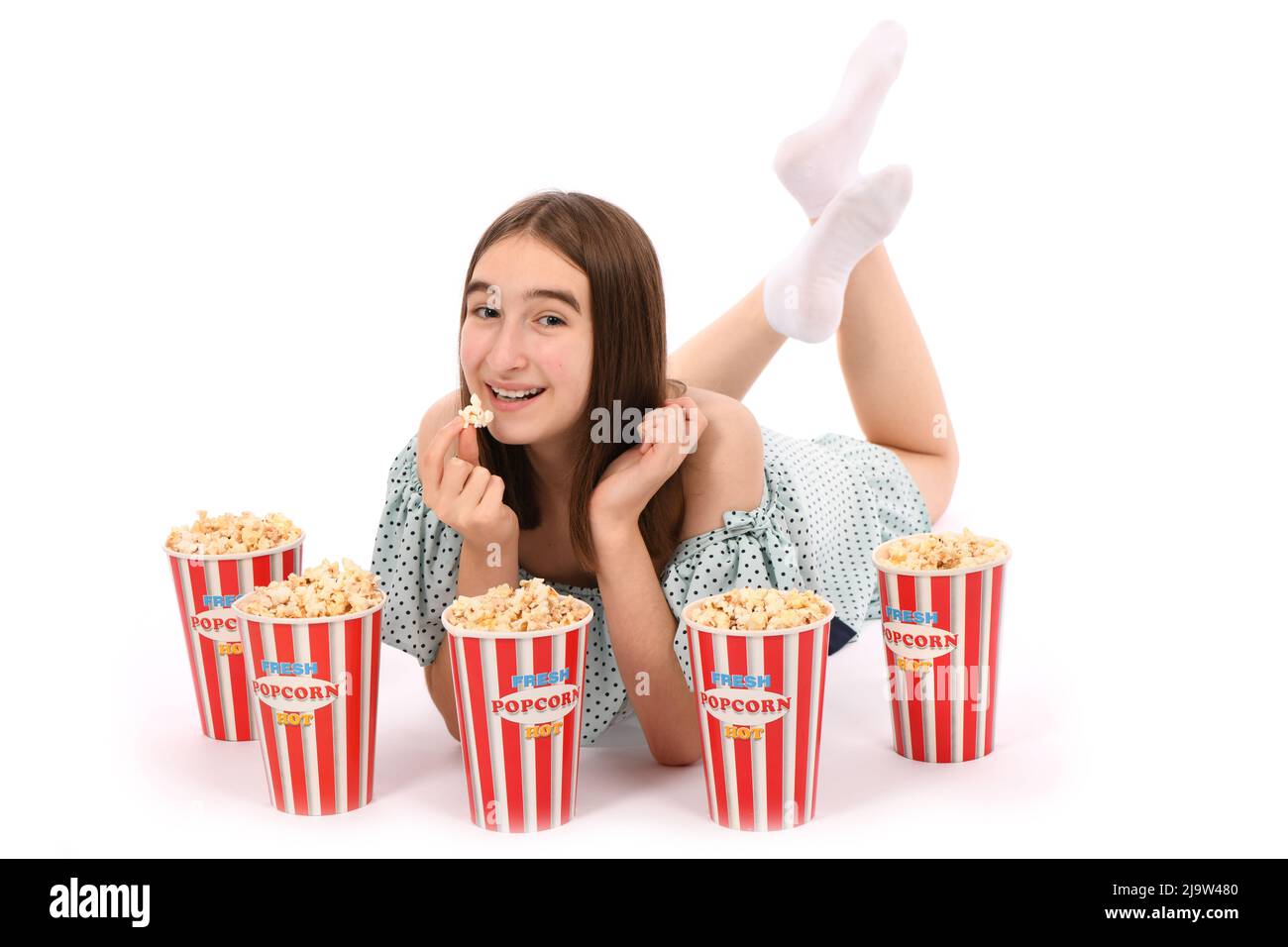 Girl lies on the floor with buckets of popcorn. Isolated on white. High ...